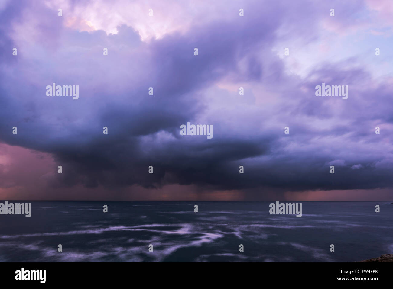 Approaching storm cloud with rain over the sea during sunrise Stock ...