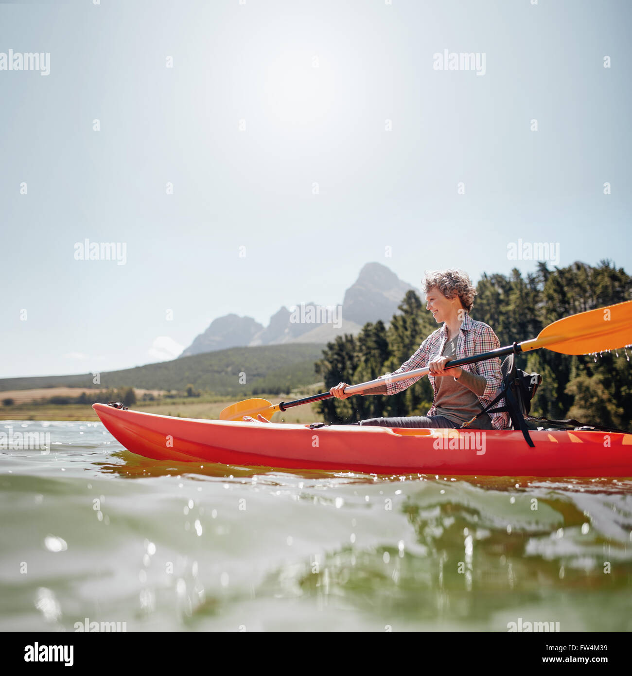 Portrait of a mature woman with kayak in a lake. Senior woman paddling ...