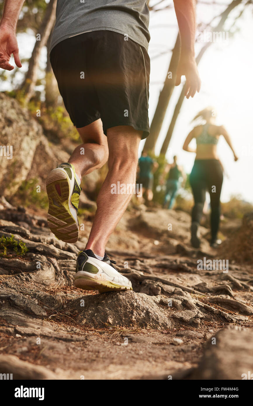 Closeup shot of a male runner on rough terrain outdoors. Trail running ...