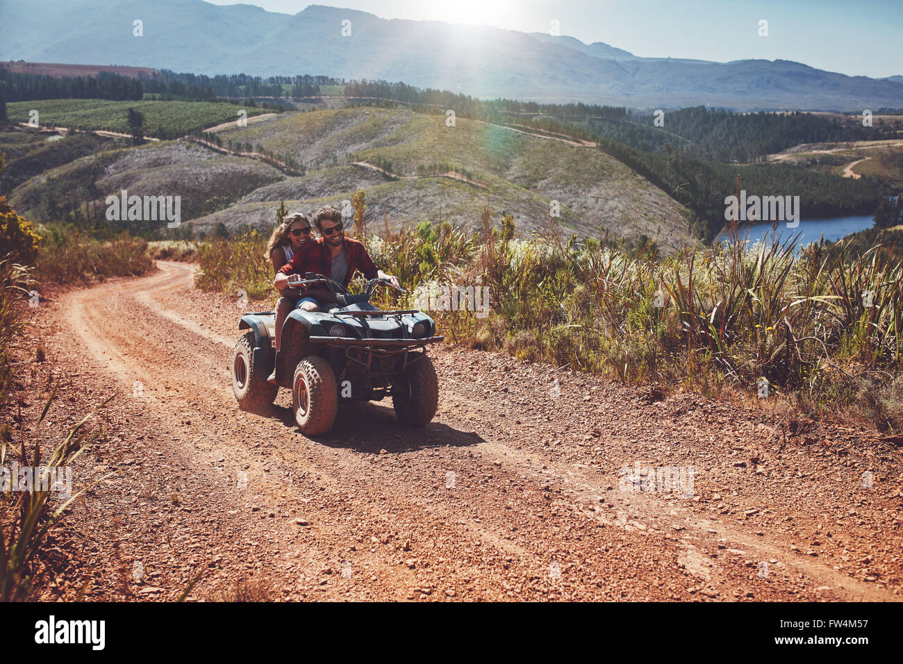 Young couple having fun in the countryside while driving on a quad bike ...