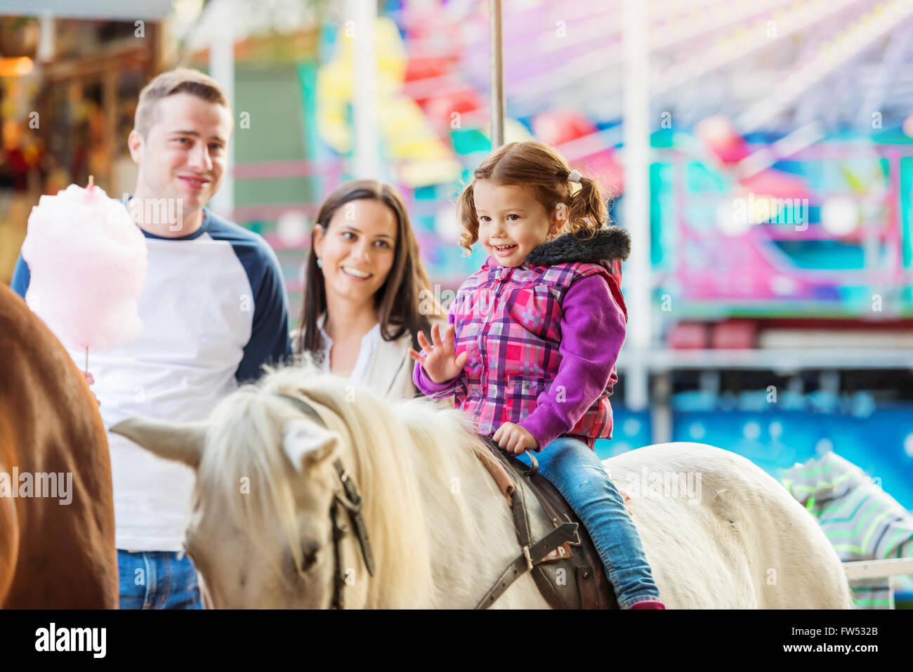 Girl enjoying pony ride, fun fair, parents watching her Stock Photo - Alamy