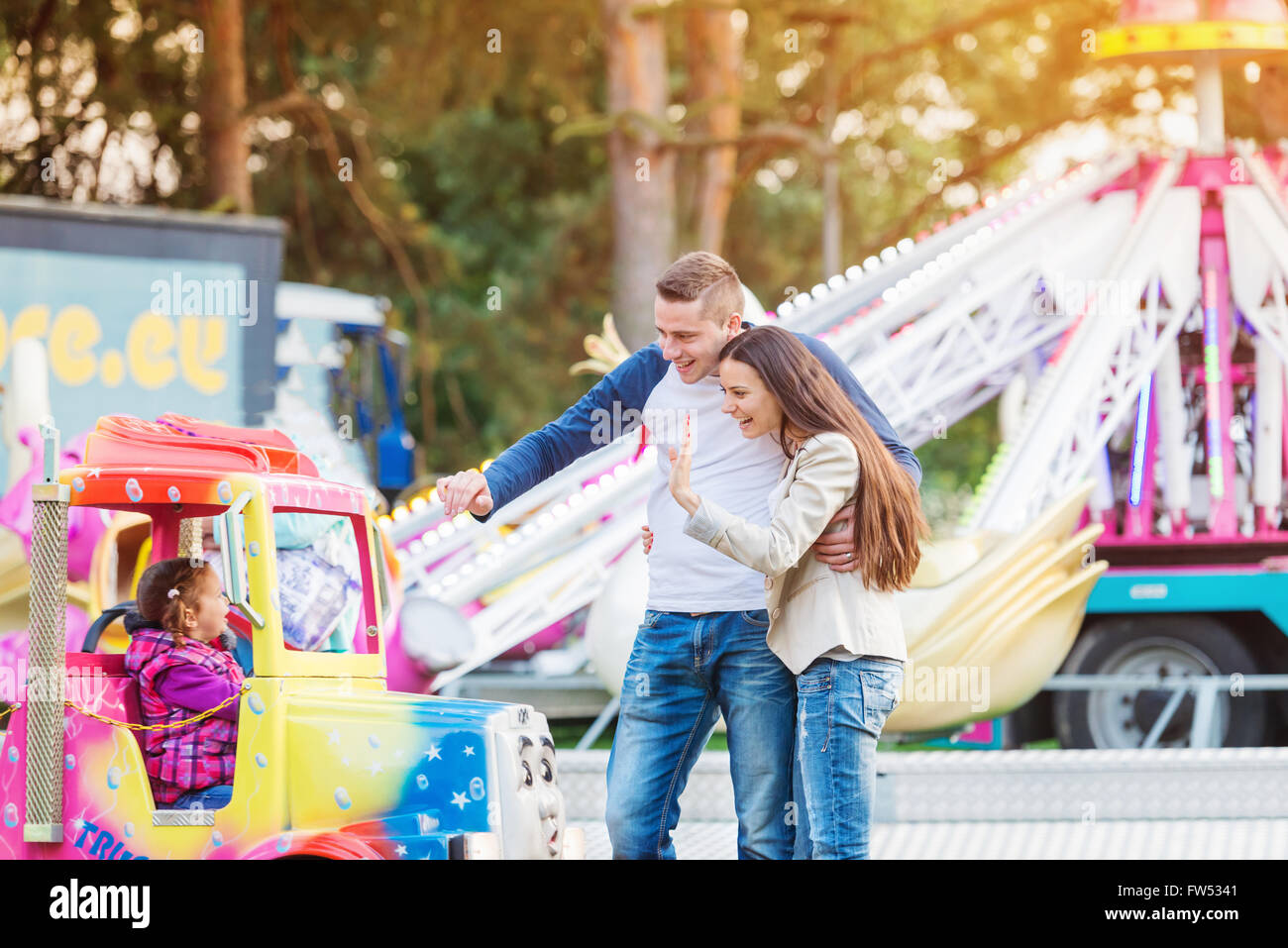 Parents at fun fair, waving their child taking ride Stock Photo - Alamy