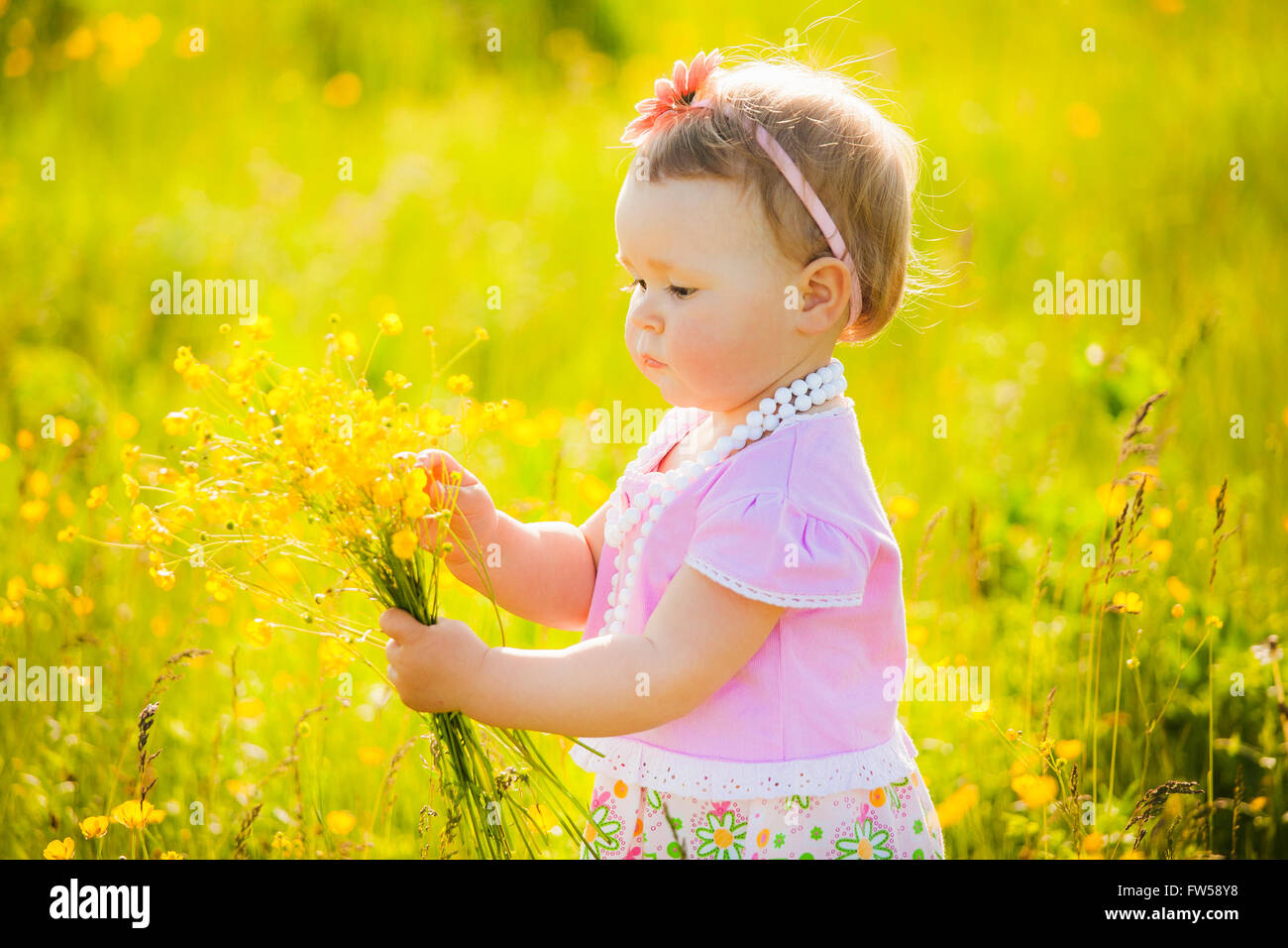 Little child playing with field flowers on spring or summer day ...