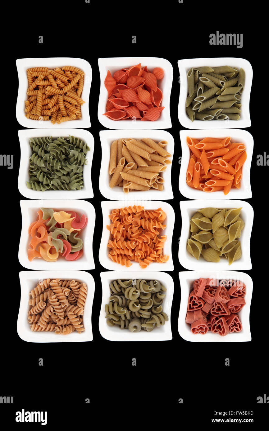 Colored italian pasta selection in china dishes over black background ...