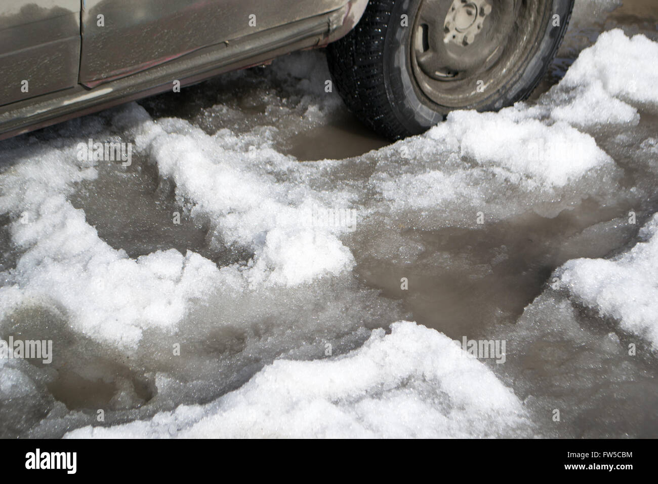 Melted snow flooded the road. Puddle closeup Stock Photo - Alamy