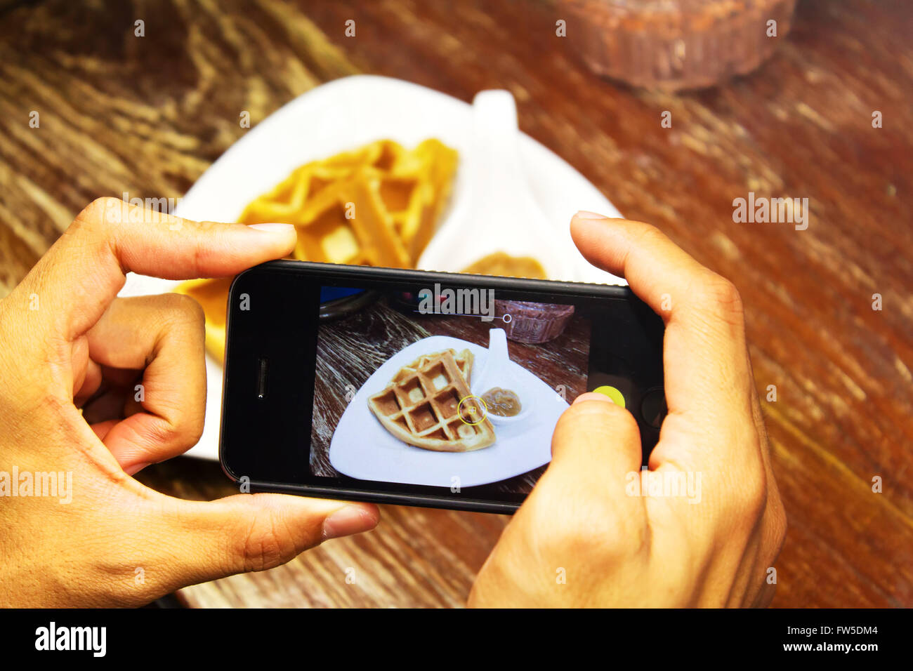 taking photo of their food with smart phone. an food on wood table ...