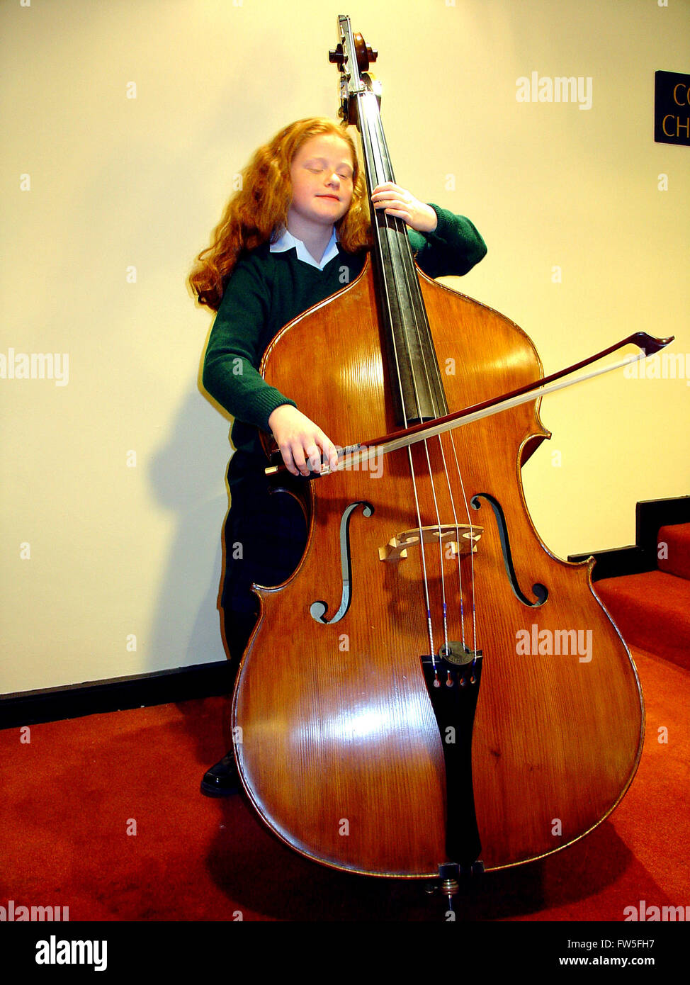 Young Irish girl playing the double bass. 10-year old child rehearsing ...