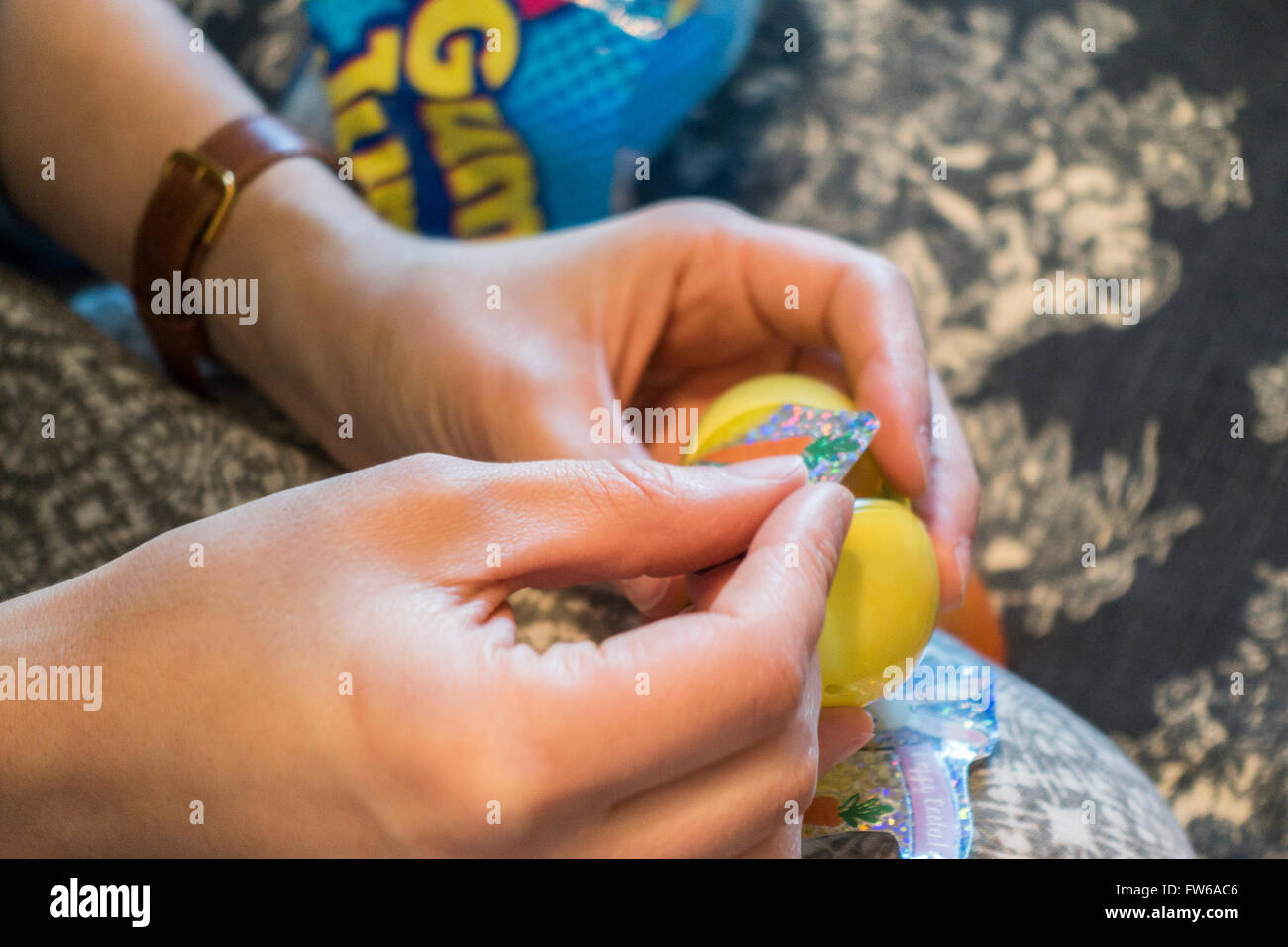 Closeup of a woman's hands putting stickers in plastic Easter eggs. USA ...