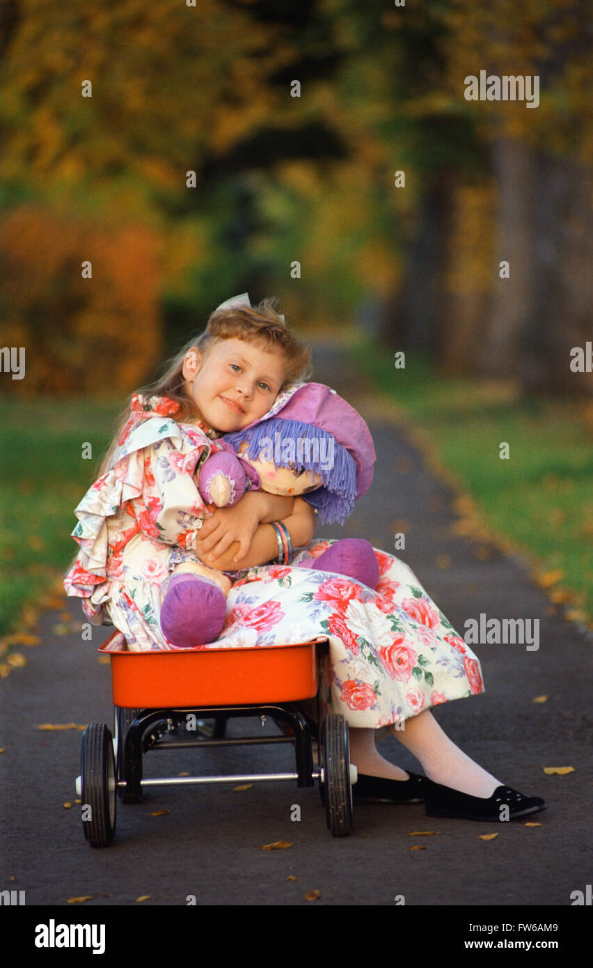 Young Girl Hugging a Rag Doll While Sitting in a Red Wagon Stock Photo ...