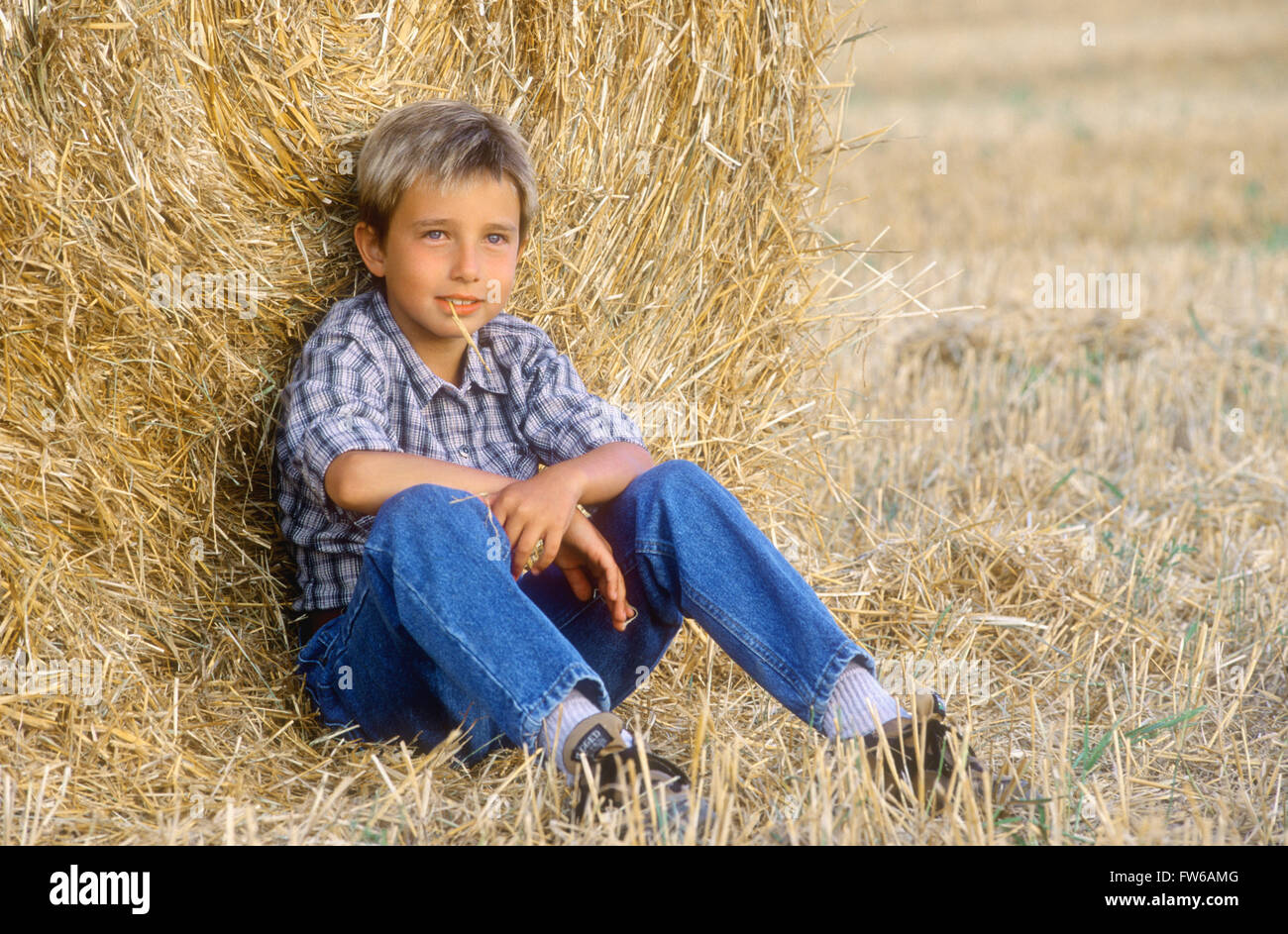 Young Boy in a Field leaning against a Round Hay Bale Stock Photo - Alamy