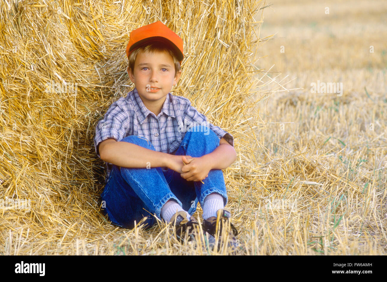 Young Boy in a Field leaning against a Round Hay Bale Stock Photo - Alamy