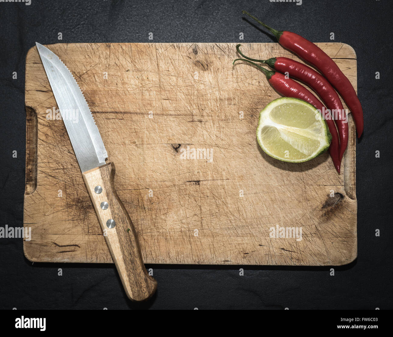 Rustic chopping board background. Lime Red Chilli pepper knife with ...