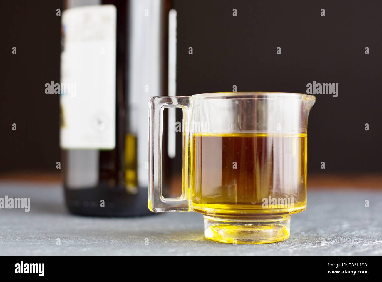 A small glass pitcher of olive oil in front of a bottle Stock Photo - Alamy