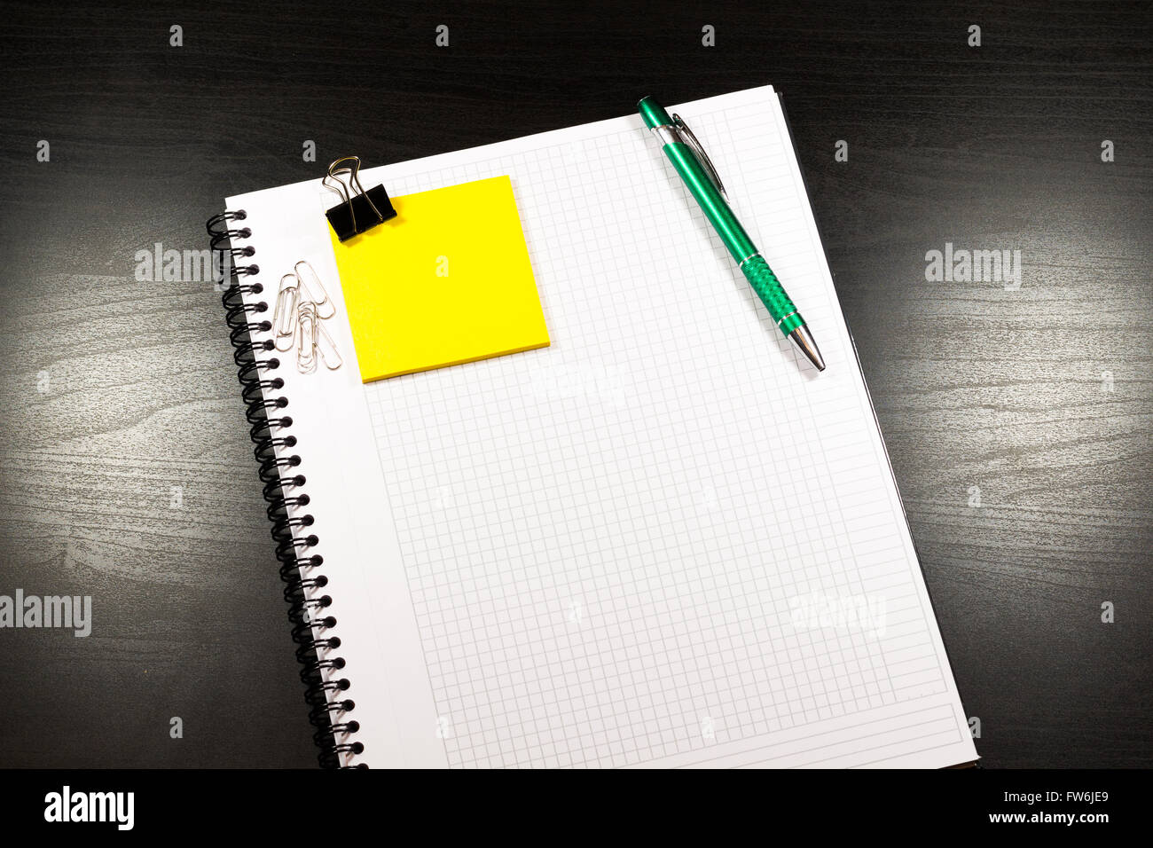 Notebook with blank paper, color sticky notes, pen and clips on a ...