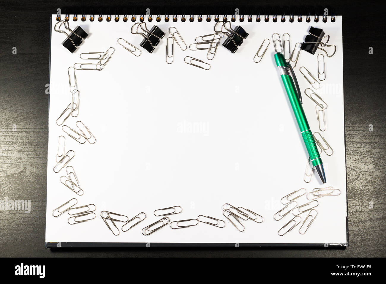 Notebook with blank paper, color sticky notes, pen and clips on a ...