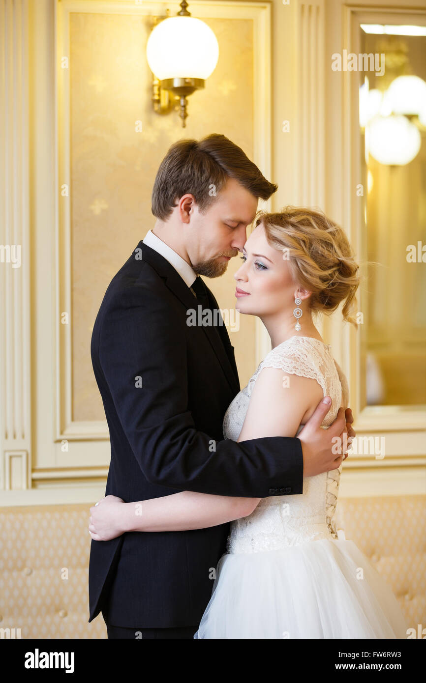 Hugging wedding couple in a bright room Stock Photo - Alamy