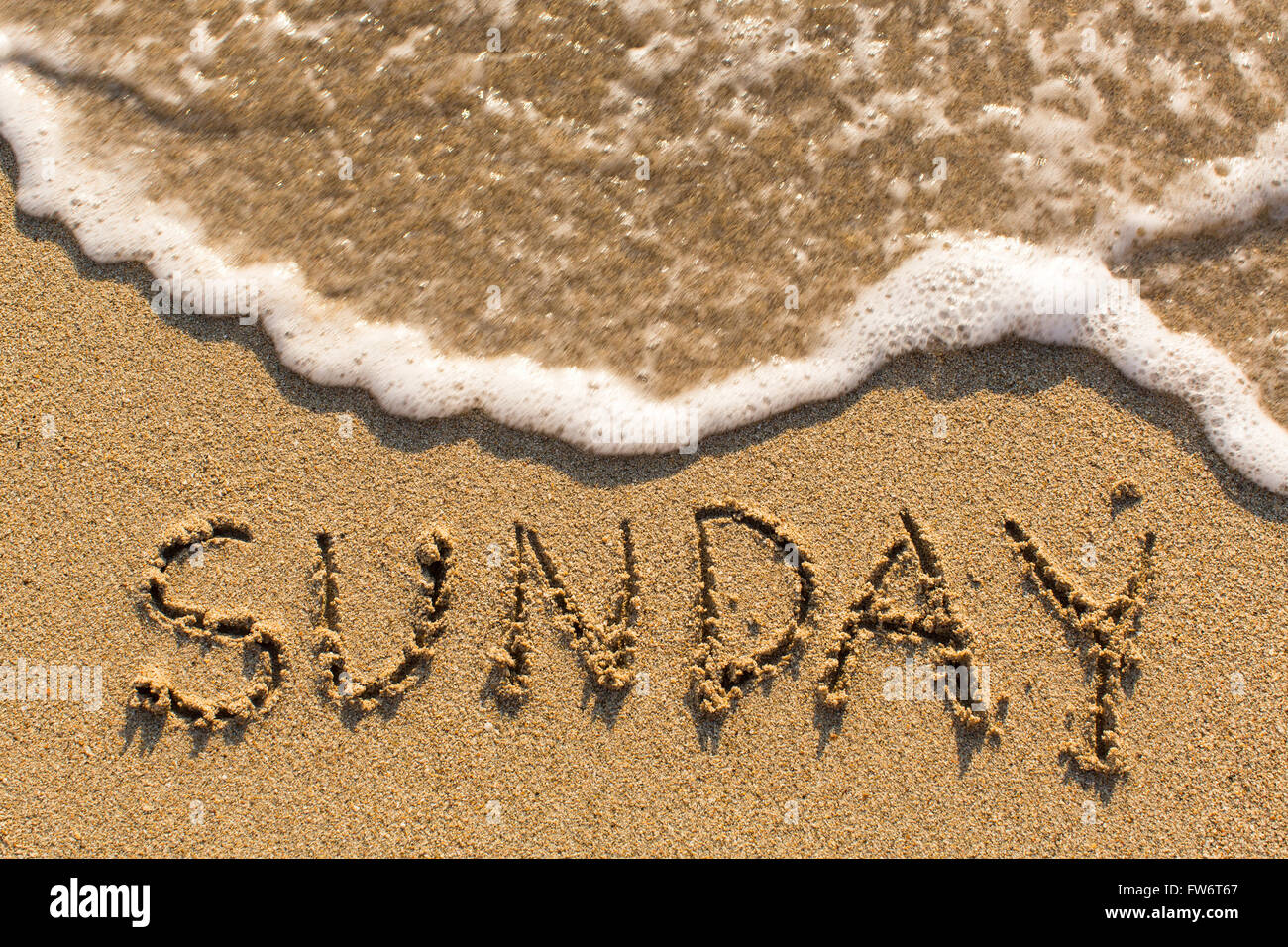 Week series - SUNDAY - written on a sandy beach with the soft wave at ...