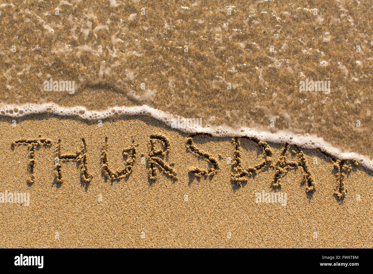 Week series - THURSDAY - written on a sandy beach with the soft wave at ...