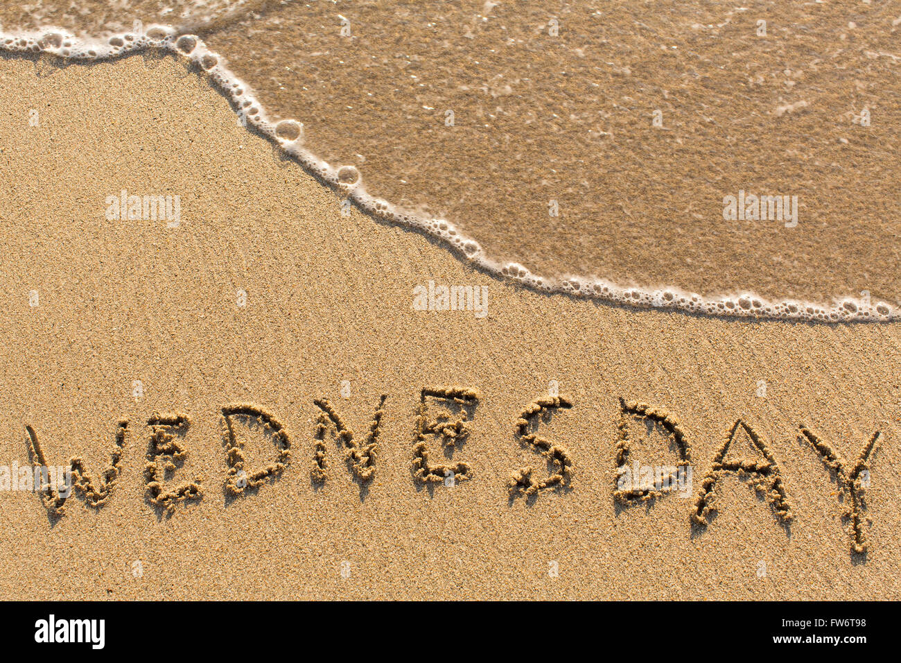 Week series - WEDNESDAY - written on a sandy beach with the soft wave ...