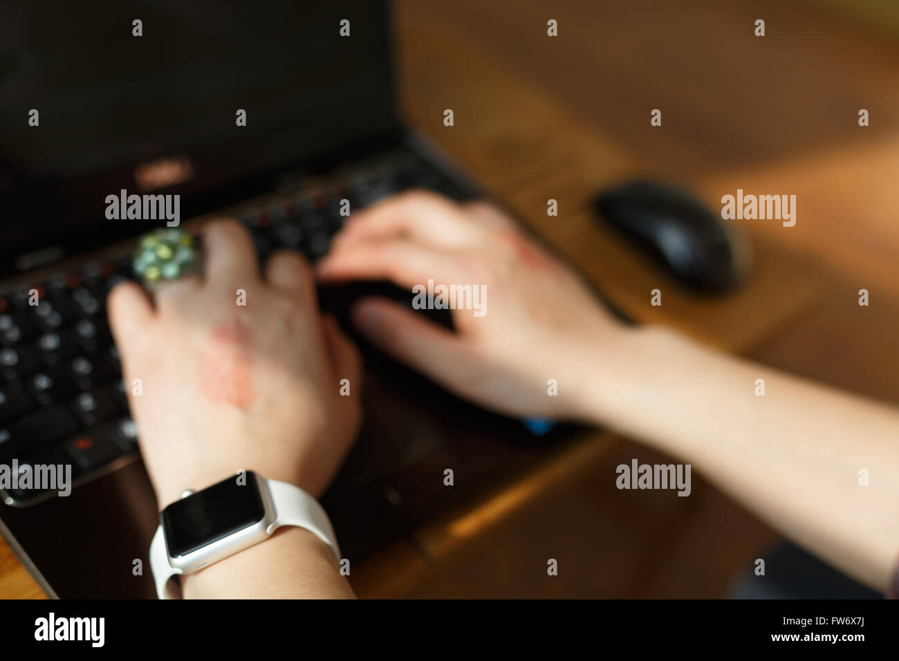 Hands of woman wearing smartwatch on the keyboard of her laptop ...