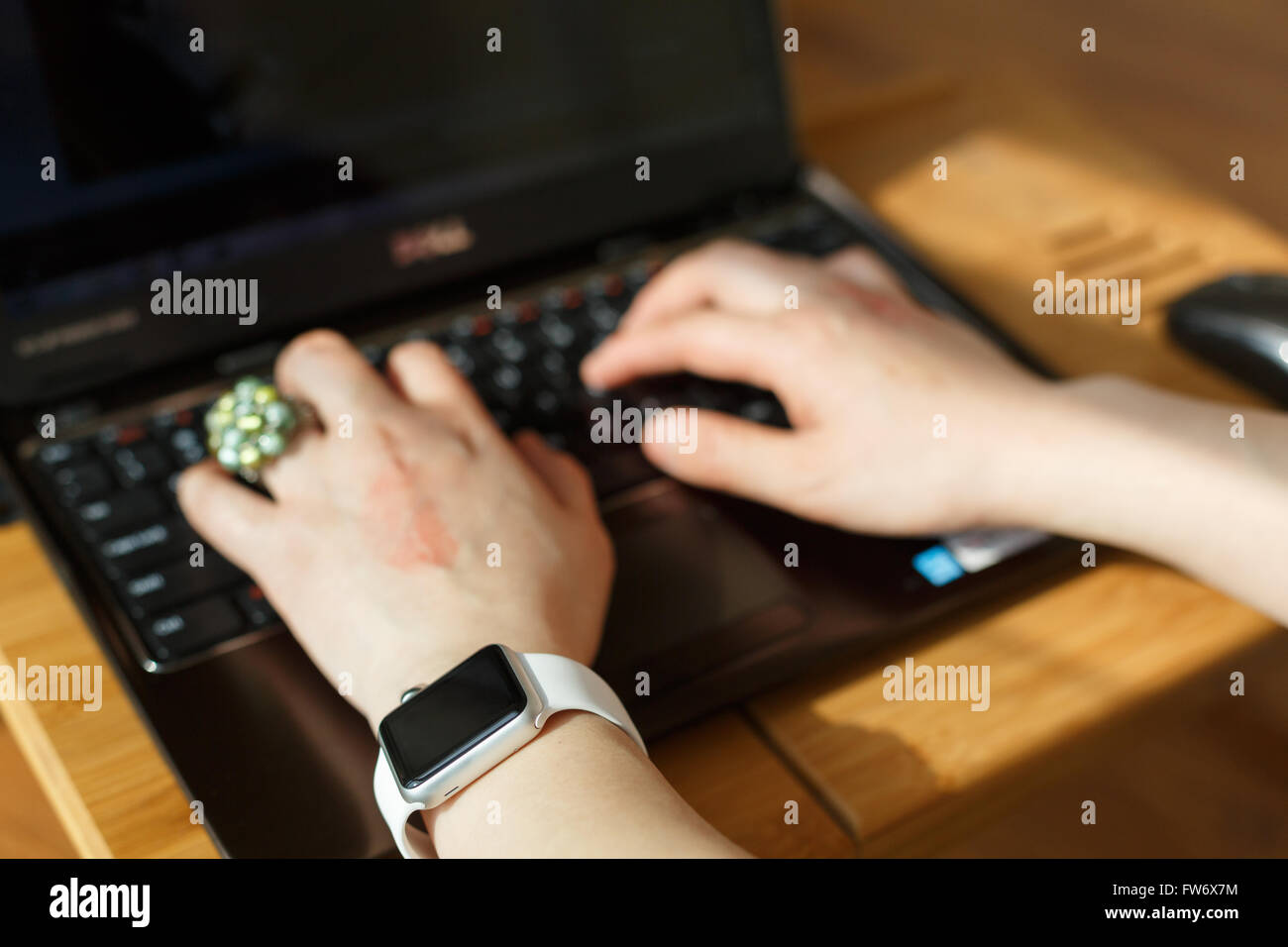 Hands of woman wearing smartwatch on the keyboard of her laptop ...