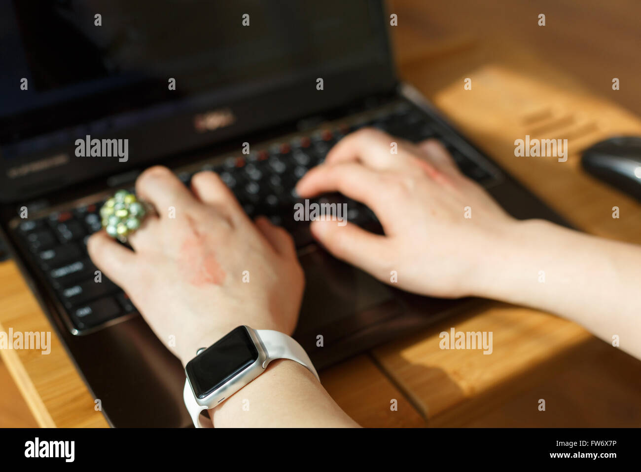 Hands of woman wearing smartwatch on the keyboard of her laptop ...