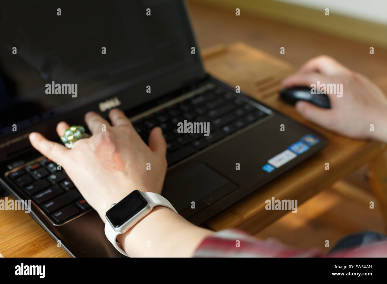 Hands of woman wearing smartwatch on the keyboard of her laptop ...