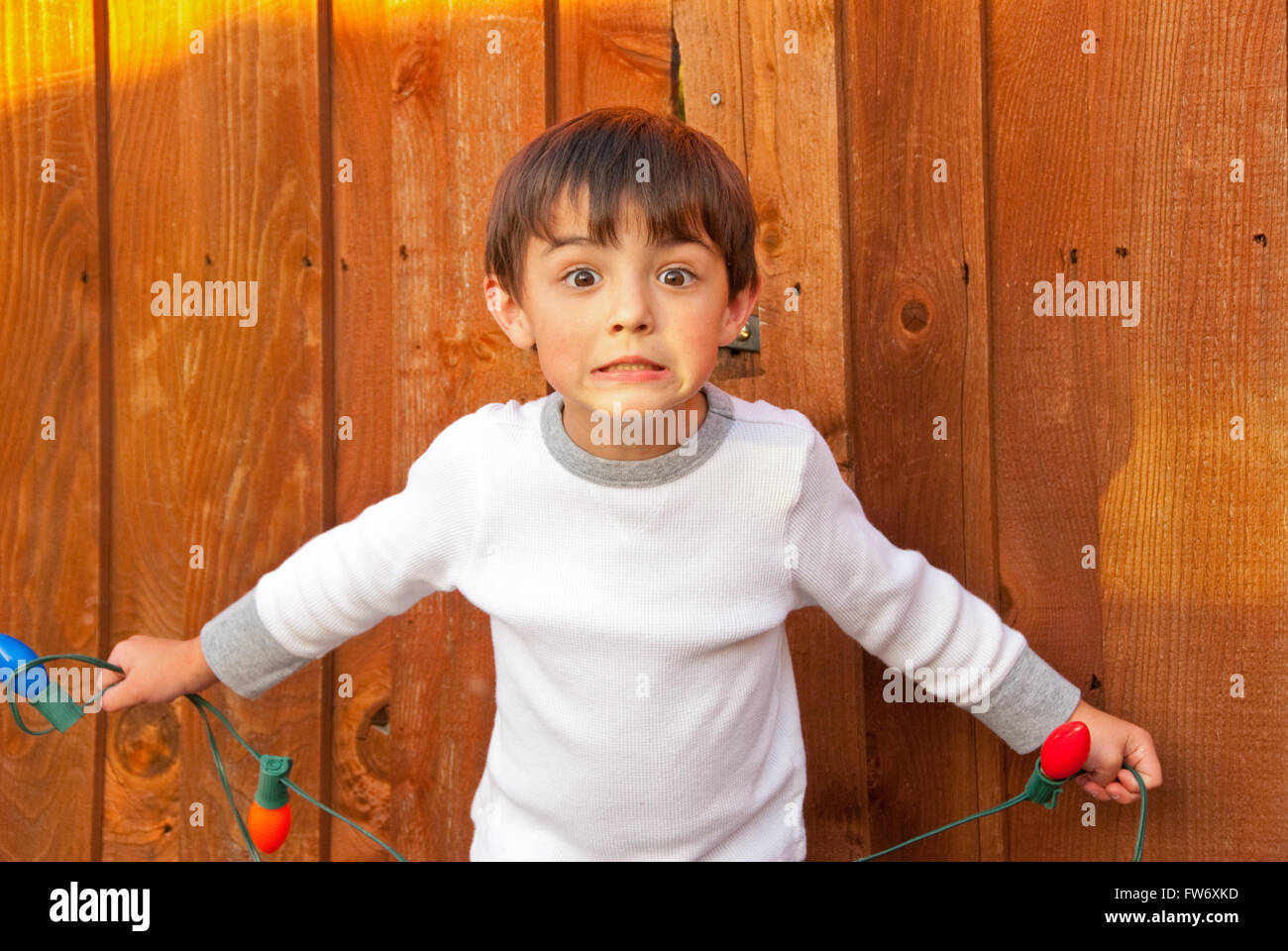 Cute young kid in front of wood fence with funny frown expression ...