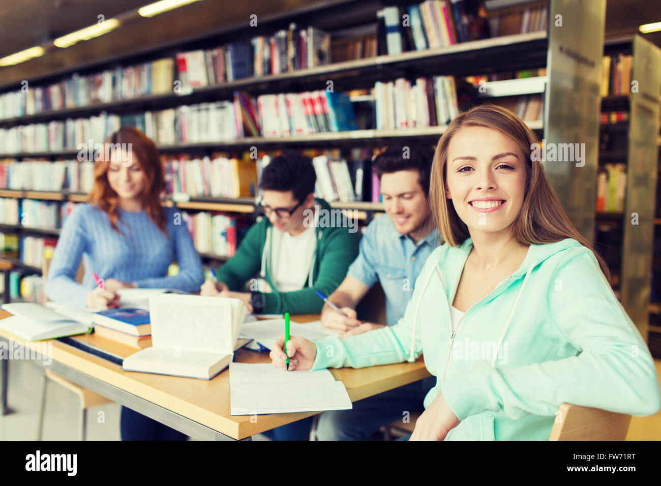 happy student girl writing to notebook in library Stock Photo - Alamy