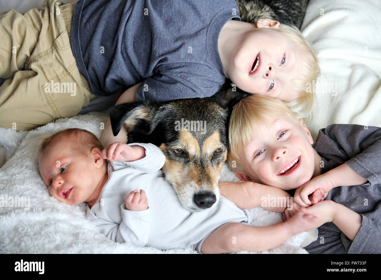 Three happy young children, including a newborn baby girl, a toddler ...