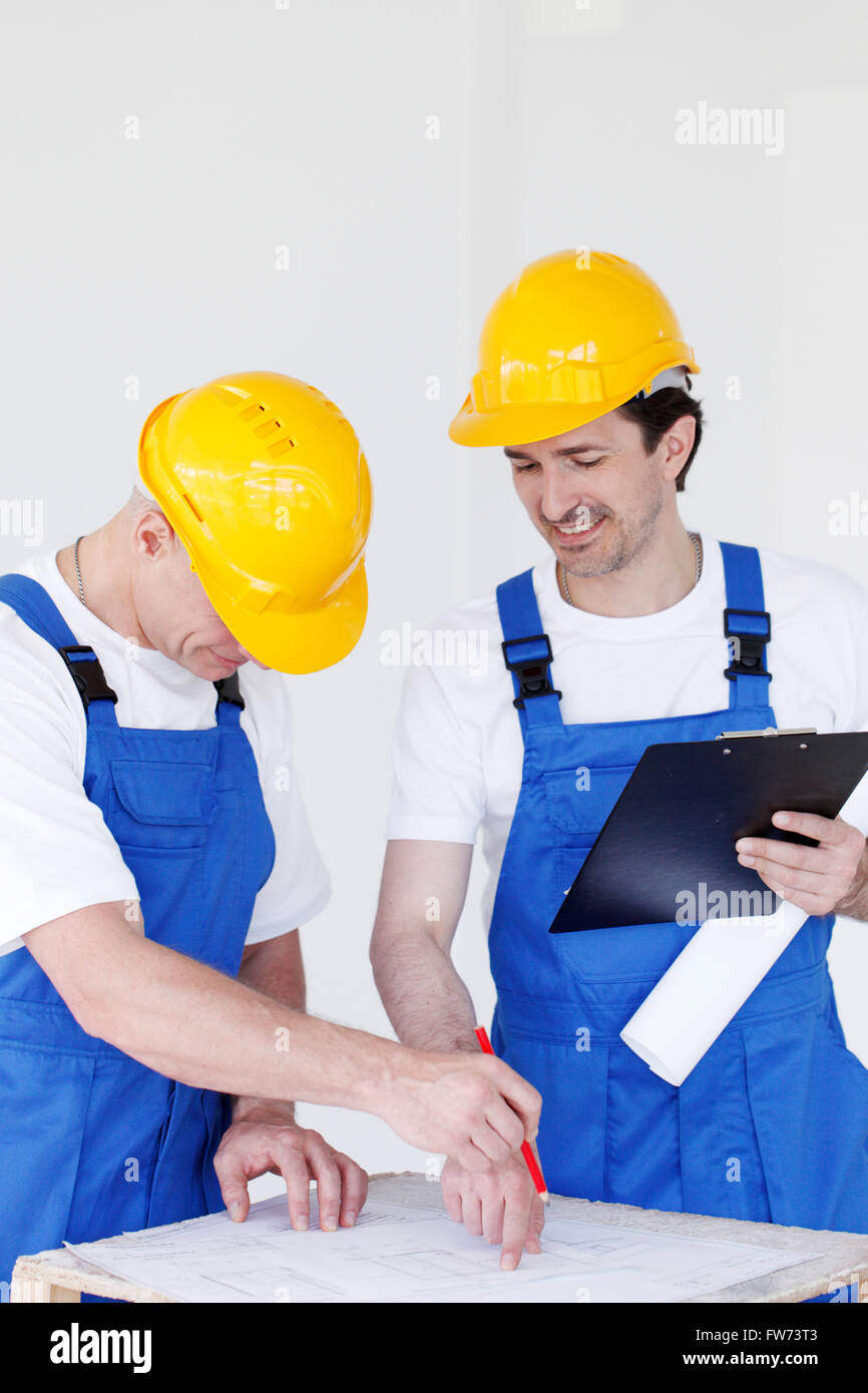 Team of builders with construction plan indoors Stock Photo - Alamy