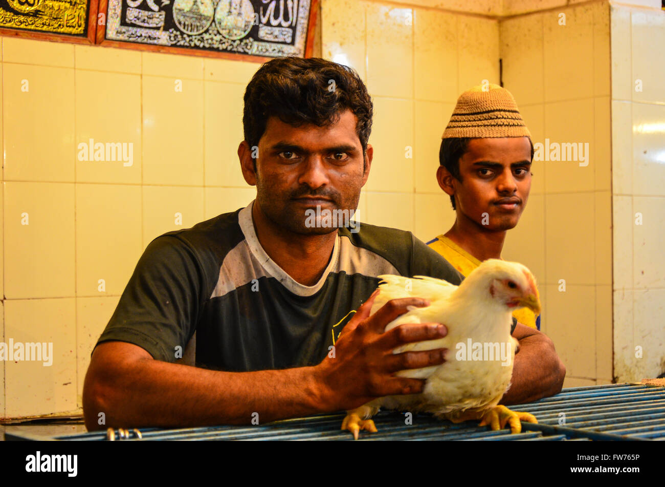 Young Indian Muslim butcher posing with live chicken in Ponda market ...