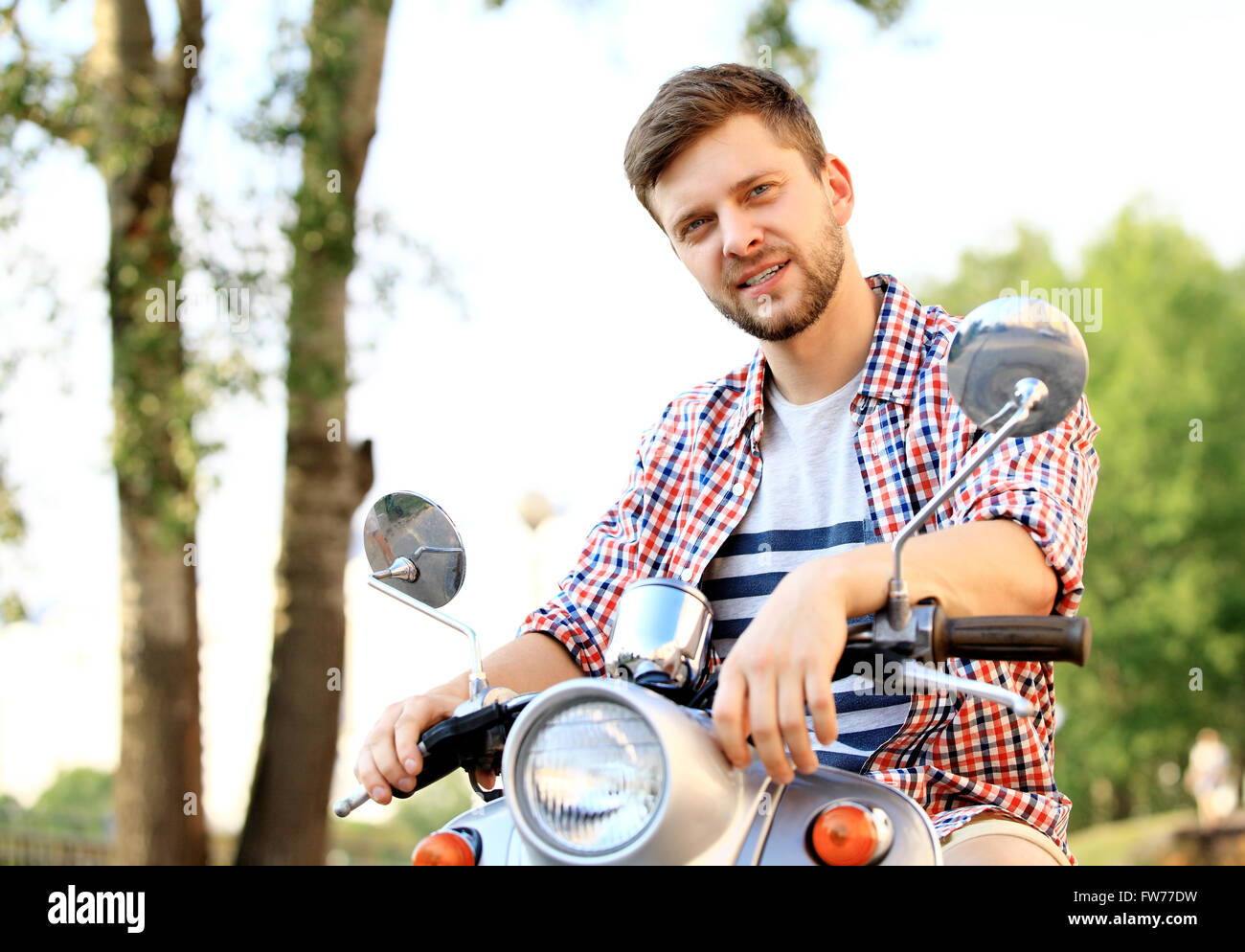 fashionable young man riding a vintage scooter in street Stock Photo ...