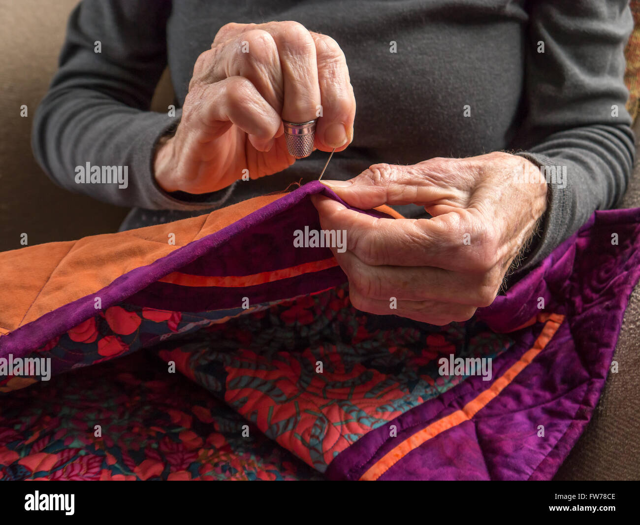 Close up color photograph of the hands of a senior woman stitching the ...