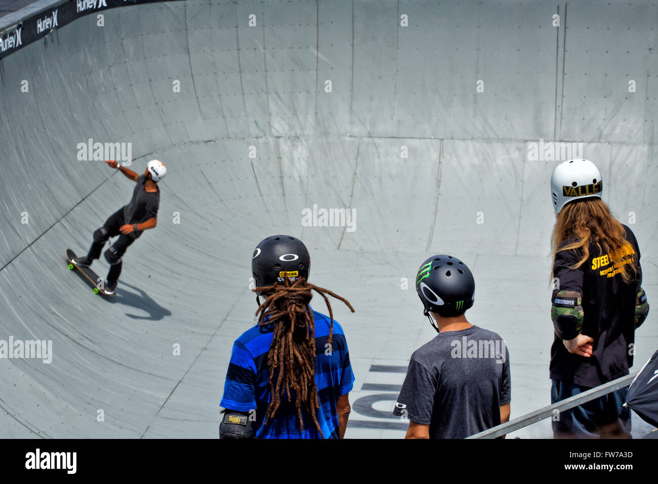A professional skateboarder performs his tricks, watched by fellow ...
