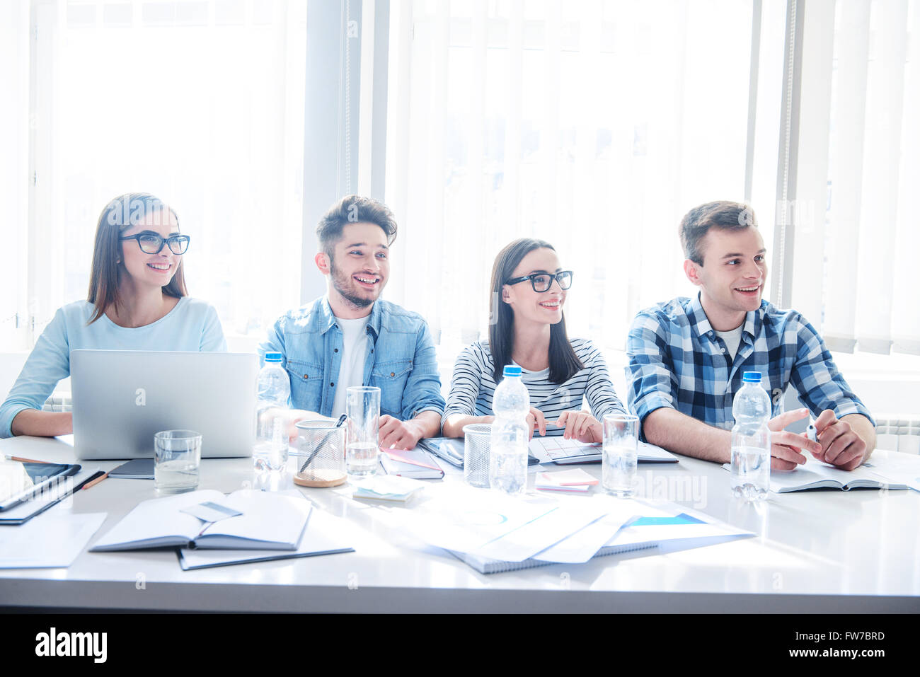 Cheerful colleagues sitting at the table Stock Photo - Alamy