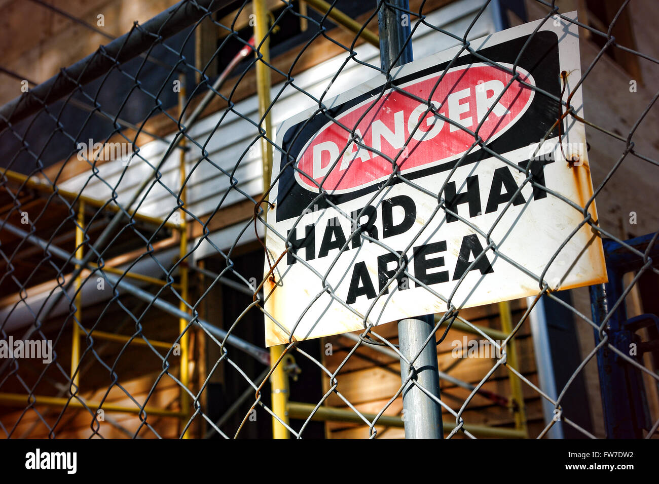 Danger hard hat area safety warning sign on a chain link fence at a ...