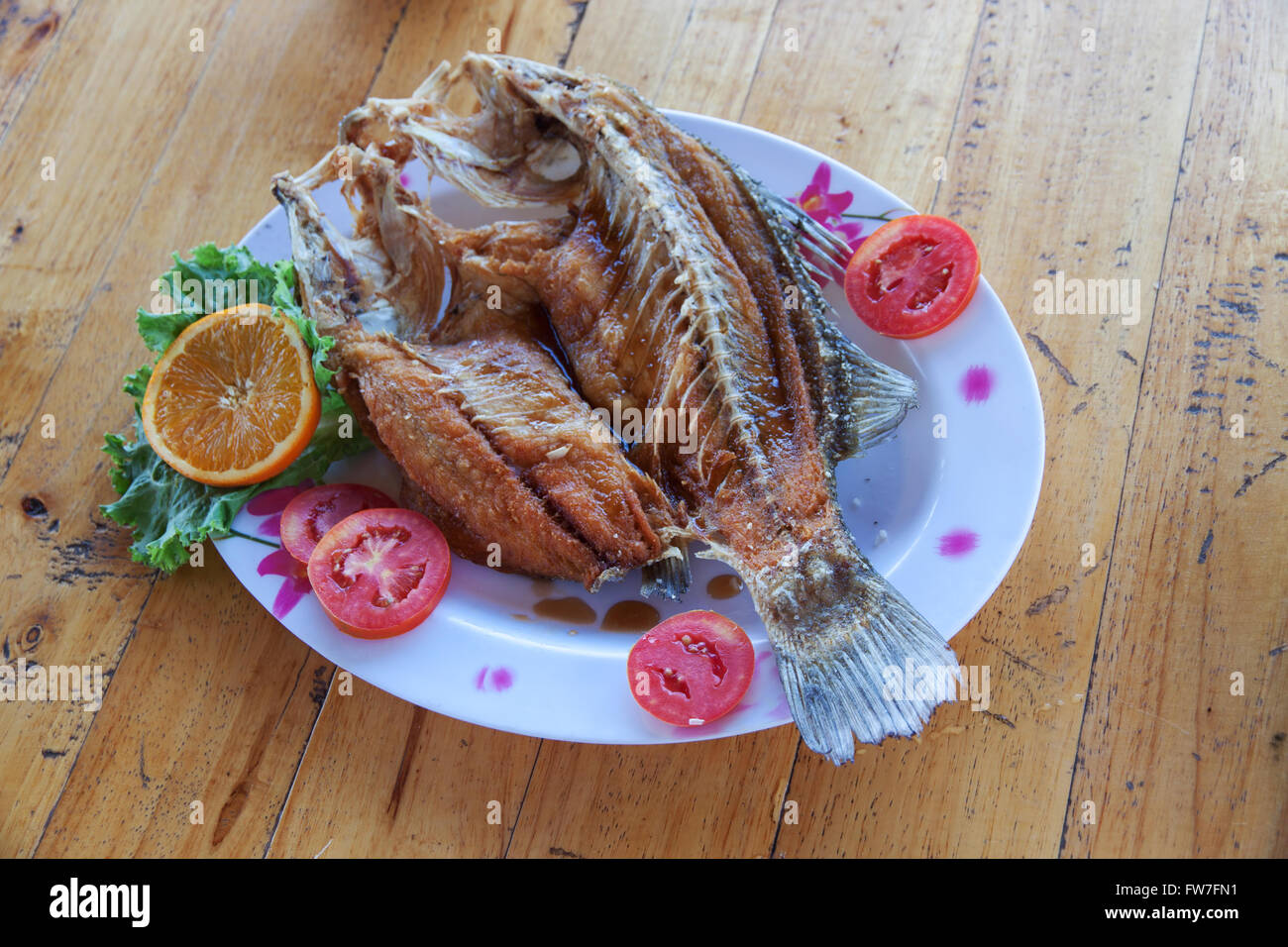 Fried snapper in plate on wood table Stock Photo - Alamy