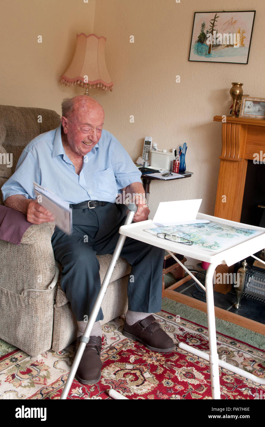 Elderly man sitting inside opening his mail Stock Photo - Alamy