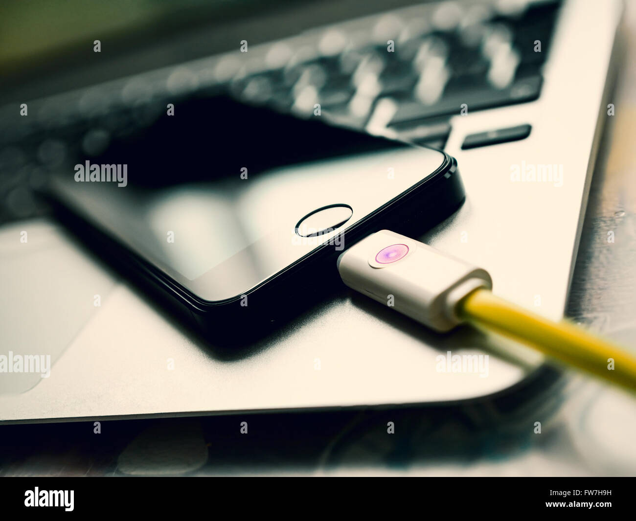 Smart phone charging on the laptop, shallow depth of field Stock Photo ...