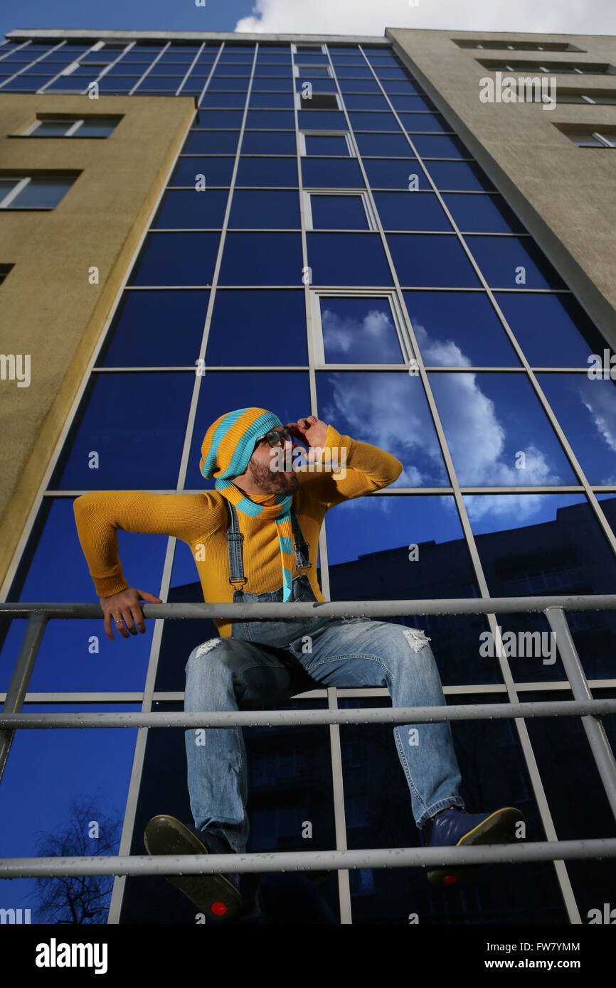 a young man in overalls on background glassed building Stock Photo - Alamy