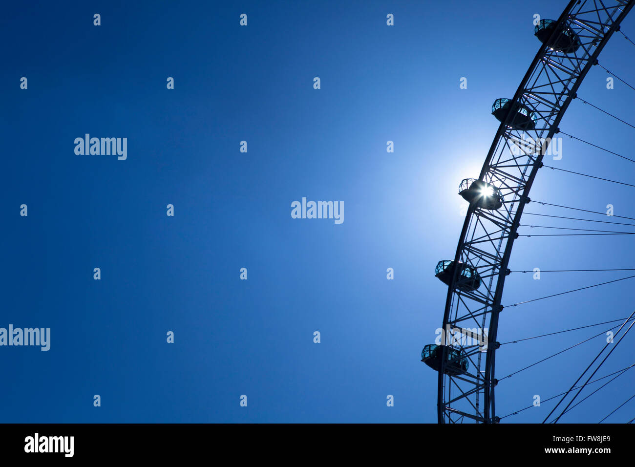 The London eye backlit by the sun in a deep blue sky in London, the ...