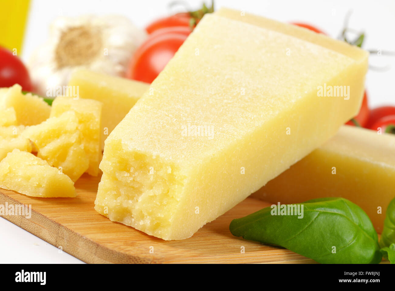 detail of fresh parmesan cheese and vegetable garnish on wooden cutting ...