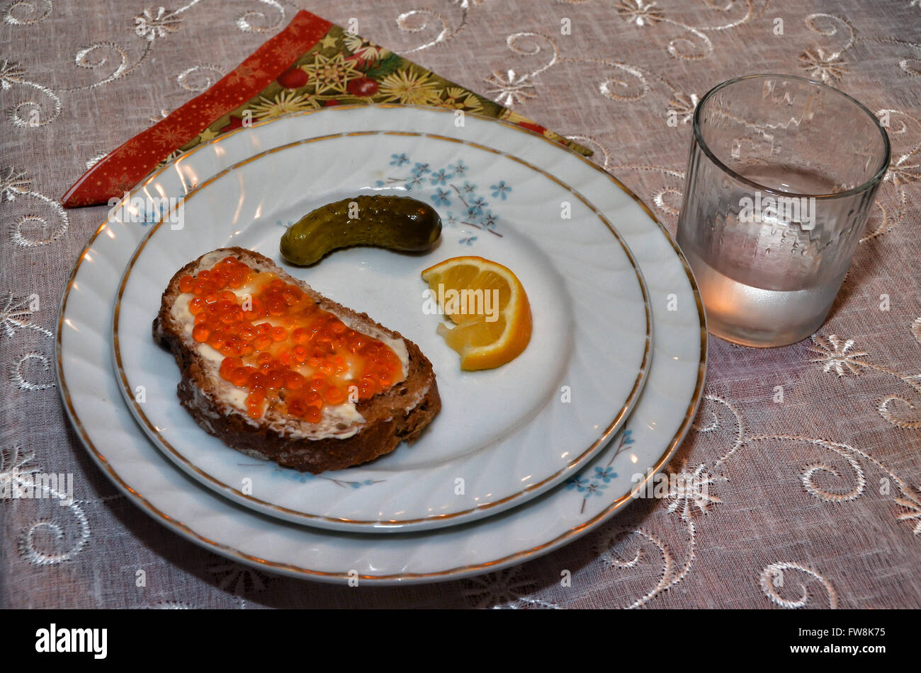 Red caviar on slice of black bread, glass of vodka, gherkin and slice ...