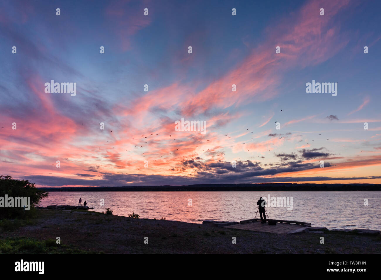 A silhouetted photographer taking a picture at sunset, on Burlington ...