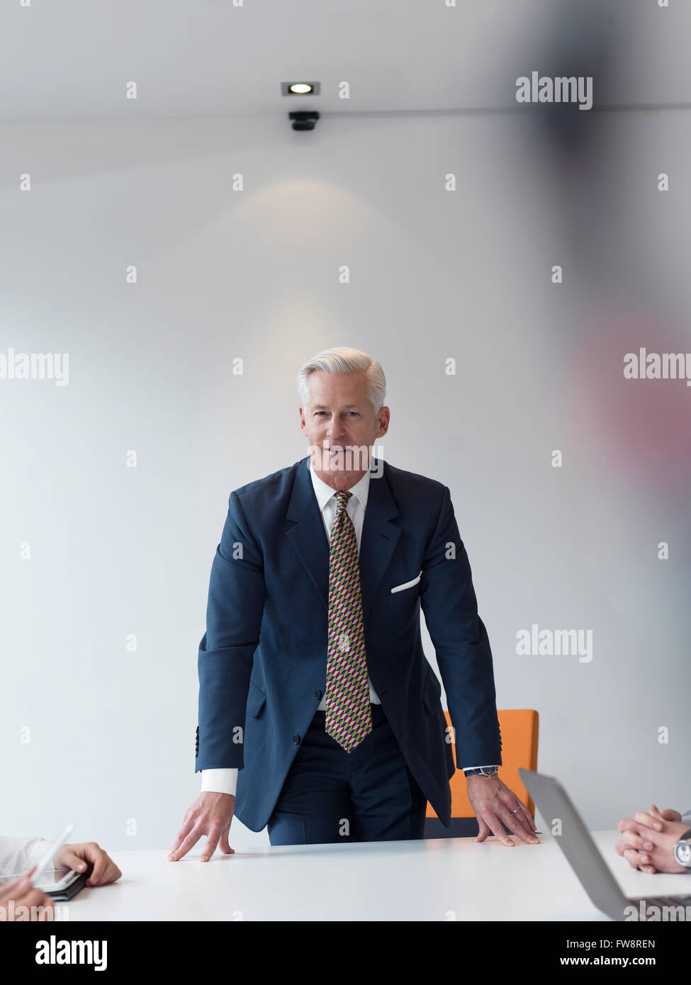 confident and handsome senior business man standing behind table in ...