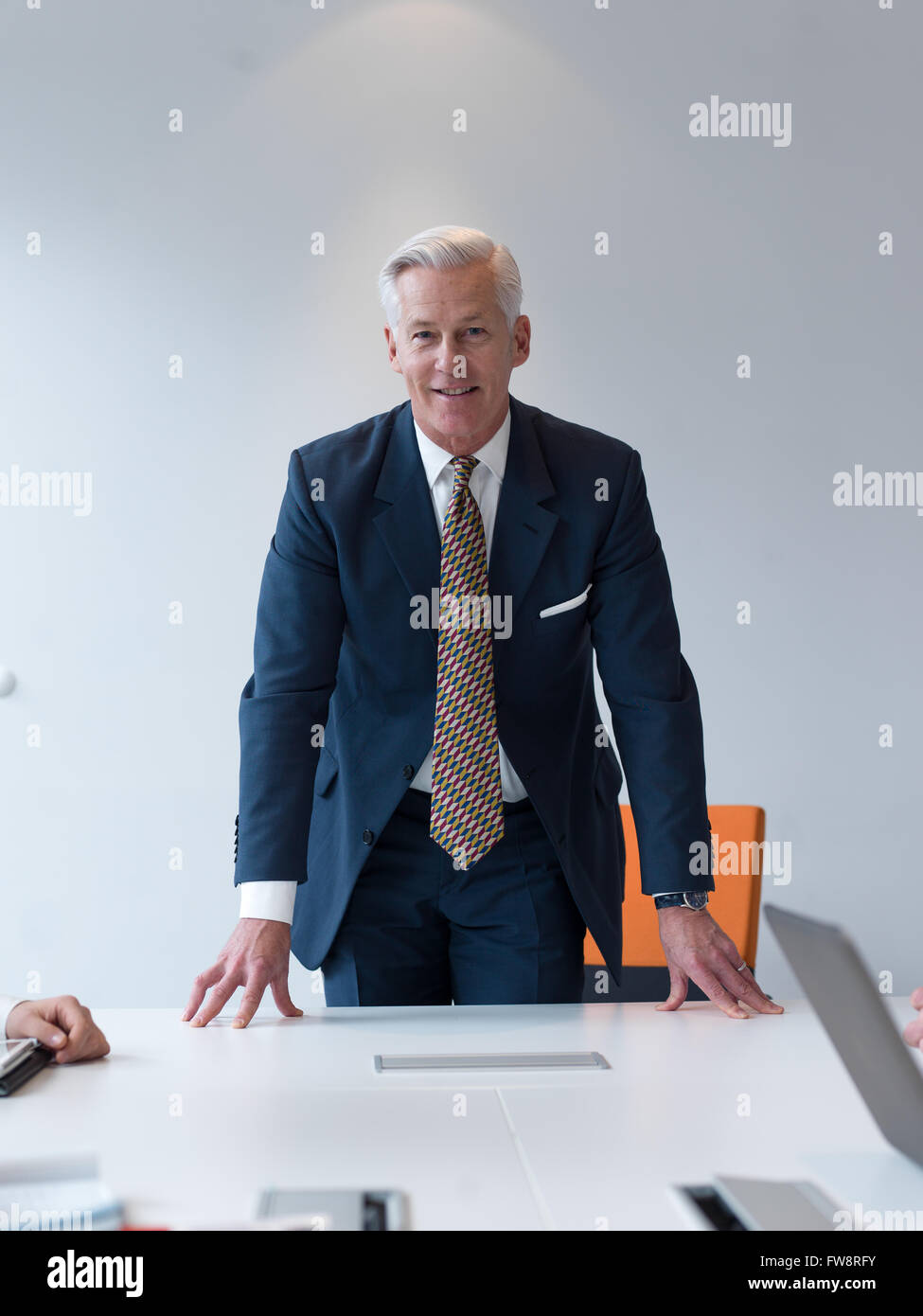 confident and handsome senior business man standing behind table in ...