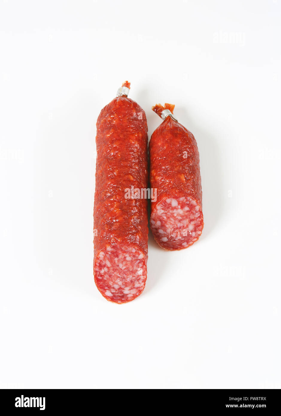 two pieces of salami sausage on white background Stock Photo - Alamy