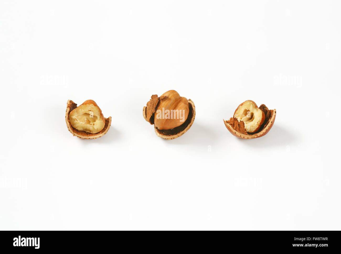 three cracked hazelnuts on white background Stock Photo - Alamy