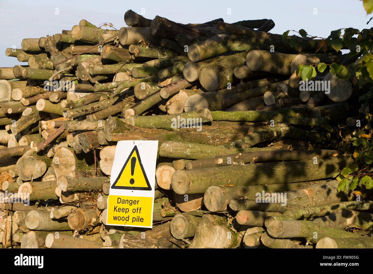 A large pile of logs with a warning sign attached asking people to keep ...